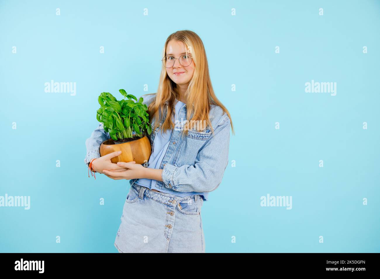 Nice teenage girl hold in hands green houseplant in wooden pot on empty ...