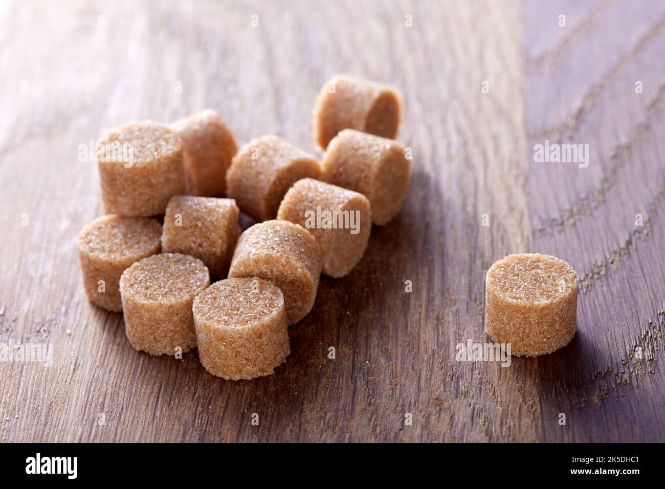 Brown round sugar forms on a old dark wooden cutting board - close up ...