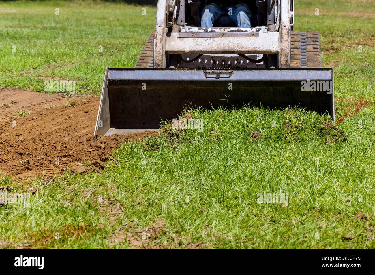 In landscaping work, bulldozer uses scoop to move earth in front of it ...