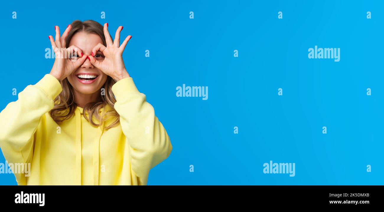 Close-up portrait cheerful and playful cute blonde girl making glasses ...