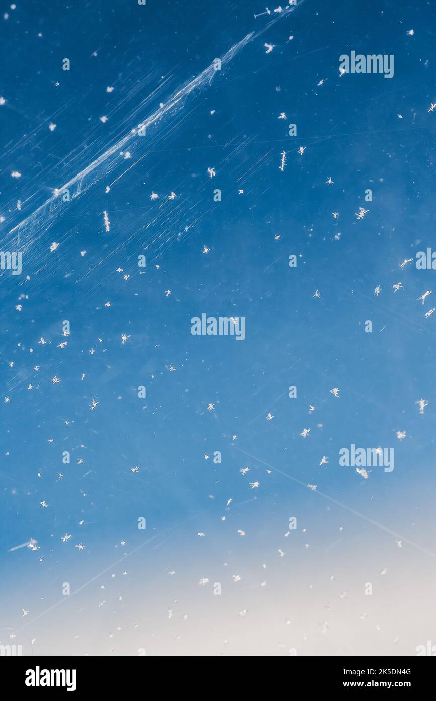 A vertical of frozen plane window with snowflakes on , blue and white ...