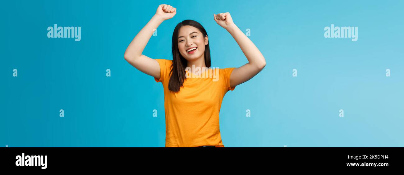 Cheerful happy optimistic cute asian girl raise hands fist pump ...