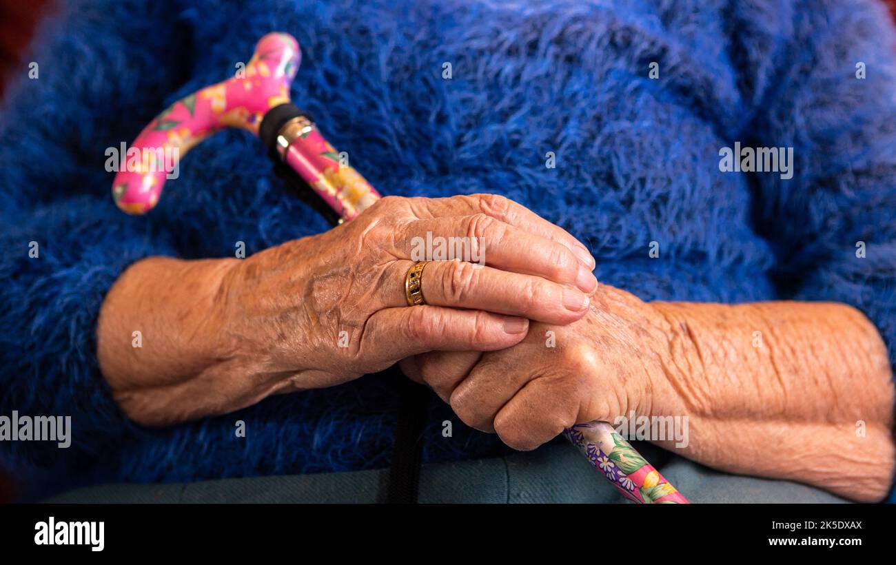 Close up of grandma holding a walking stick while she sitting on the ...