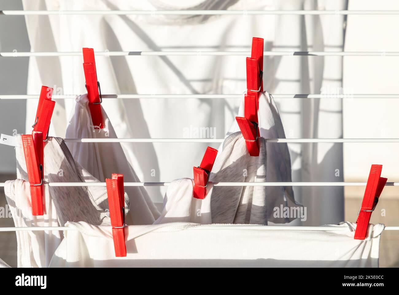 white shirt drying in the sun with red clothes pins in detail Stock ...