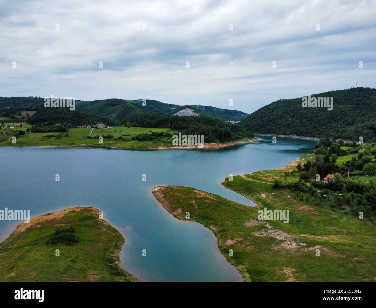An aerial view of a beautiful small lake surrounded by green mountains ...