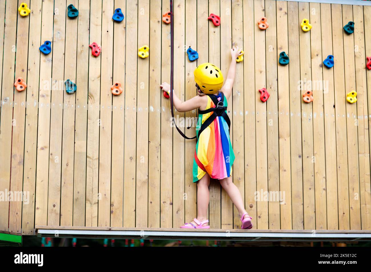 Child in forest adventure park. Kids climb on high rope trail. Agility ...