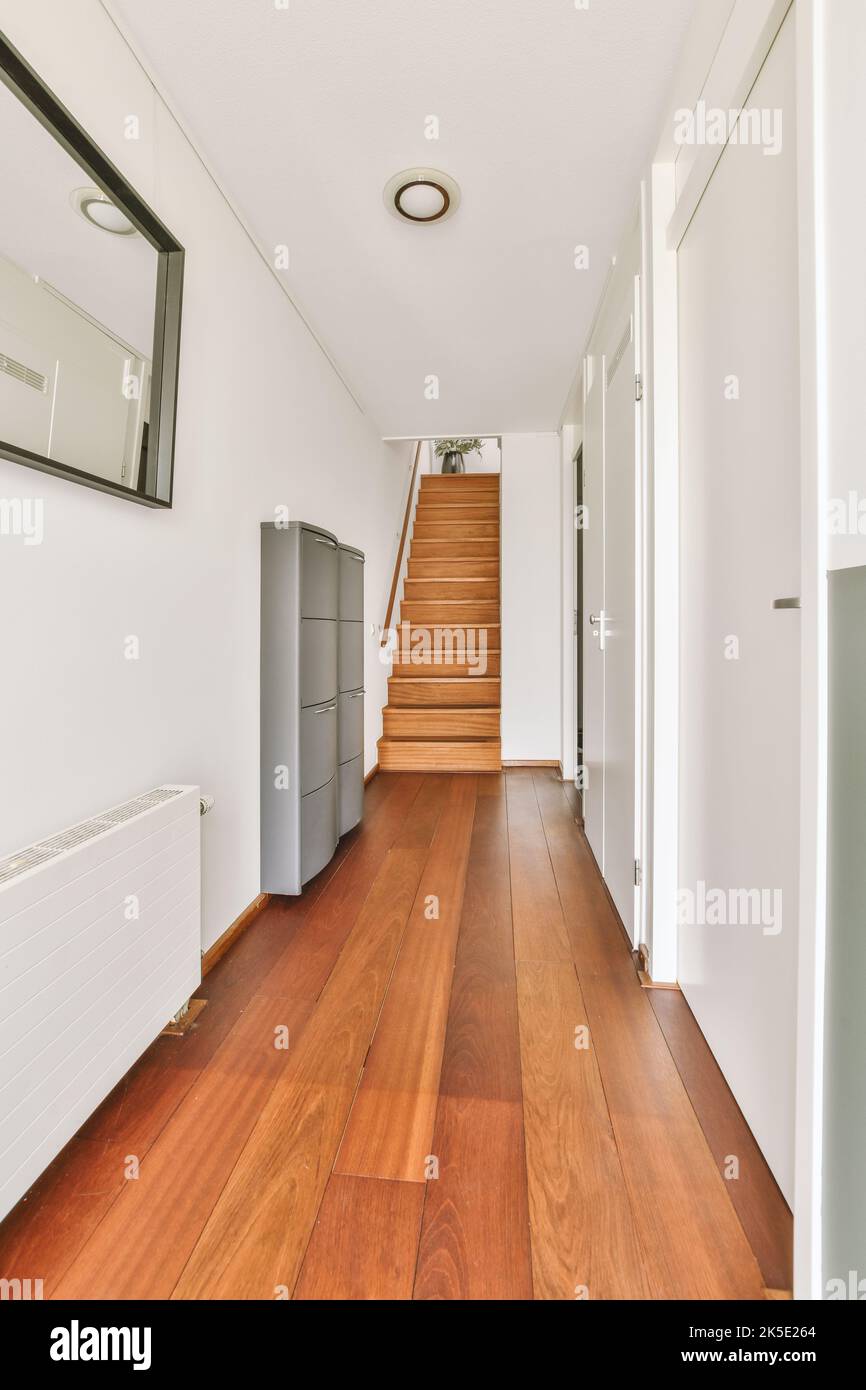 White hallway with wooden stairway leading to second floor of modern ...
