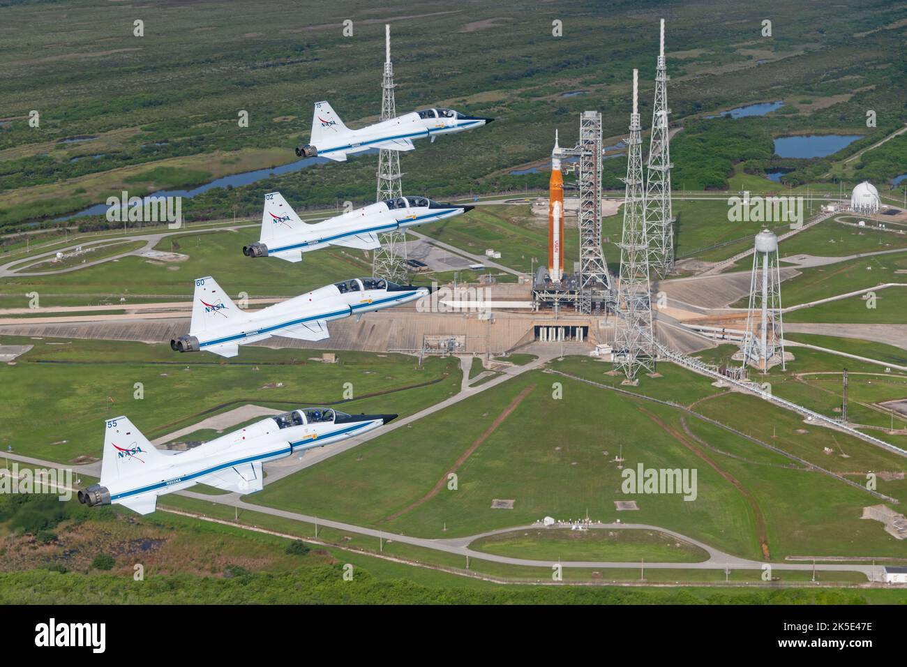 NASA T-38s fly in formation above the Space Launch System (SLS) rocket on Launch Pad 39B ...