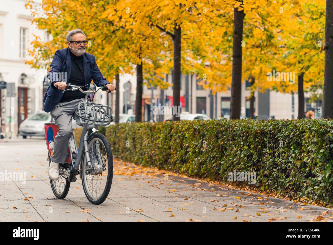 Colours of autumn. 60-year-old happy gray-haired man cycling on ...