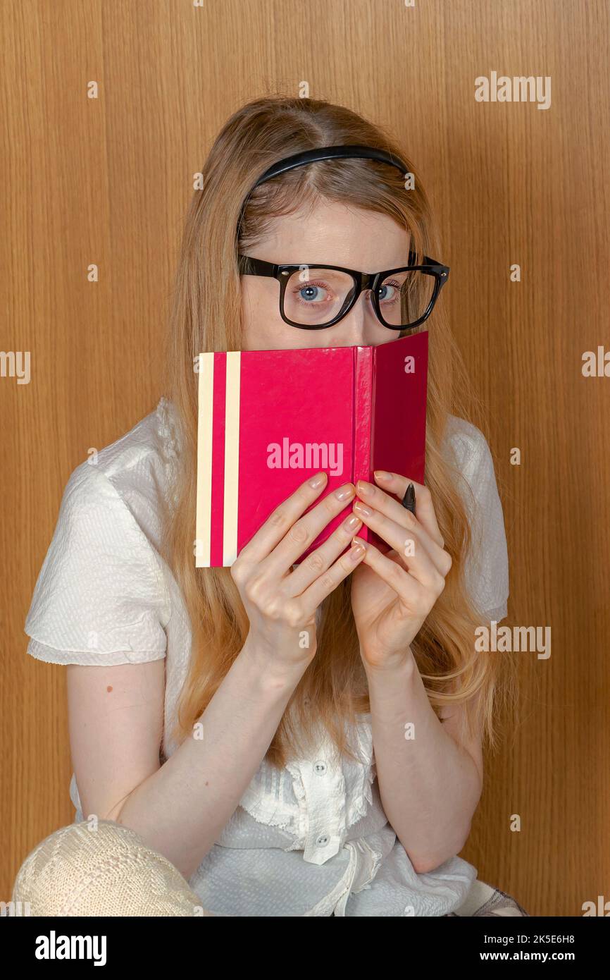 Young student girl portrait holding open notebook in front of her face ...