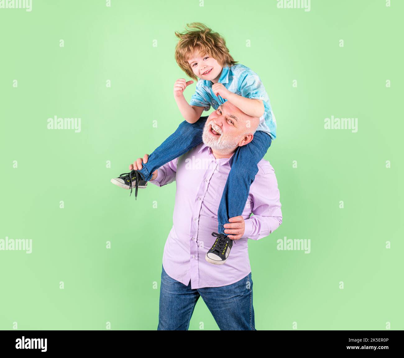 Young grandson and old grandfather piggyback ride with funny face ...