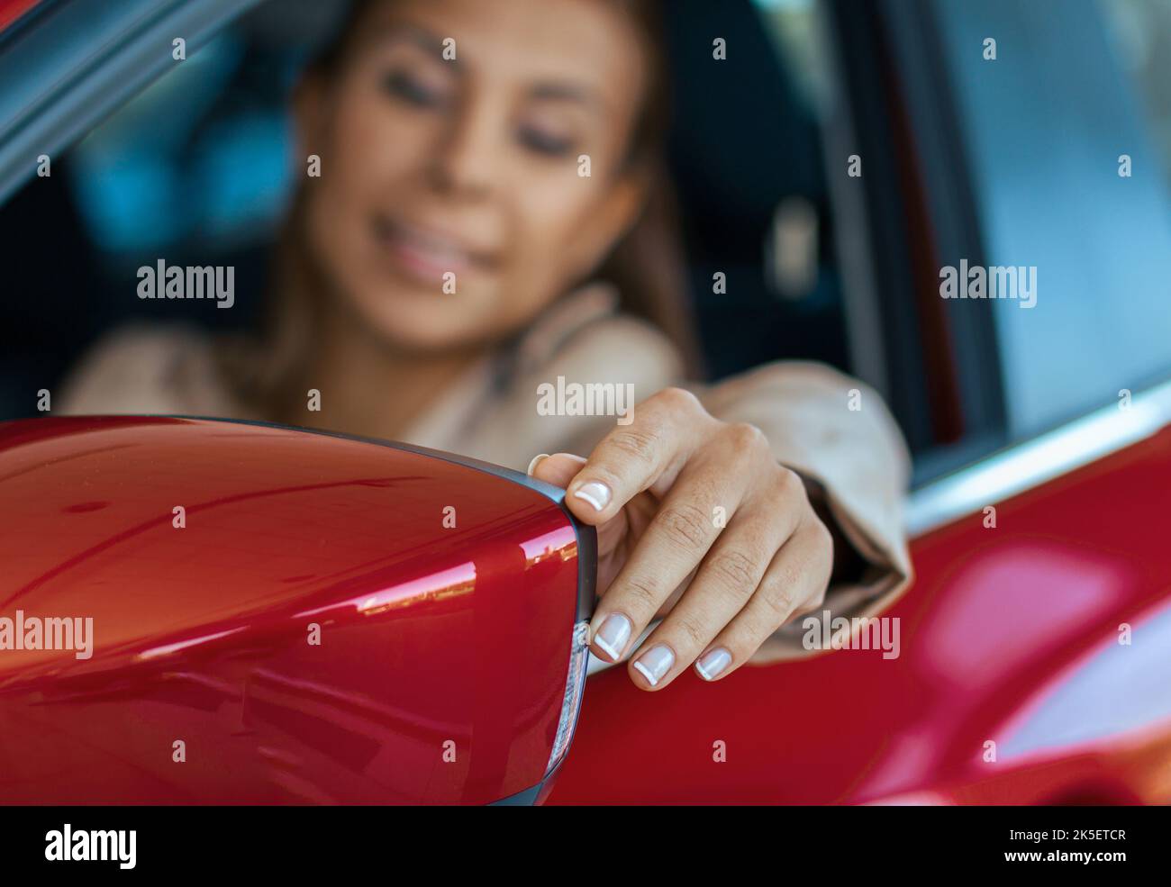 Happy young woman sitting inside her new car and looking at sideview mirror Stock Photo - Alamy