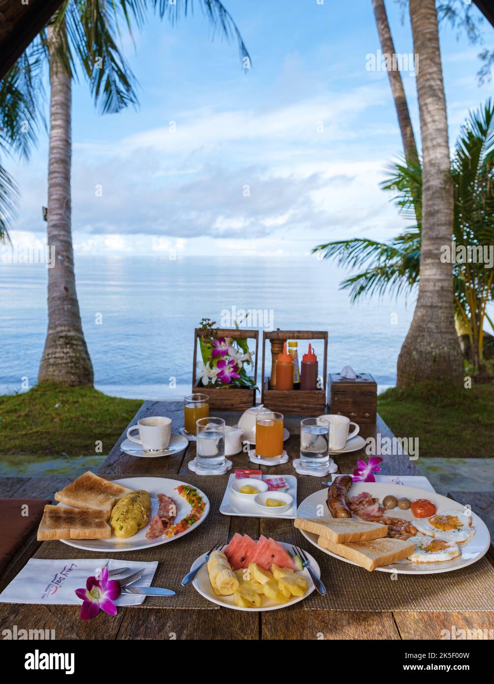 breakfast table on the beach with palm trees in Thailand. colorful ...