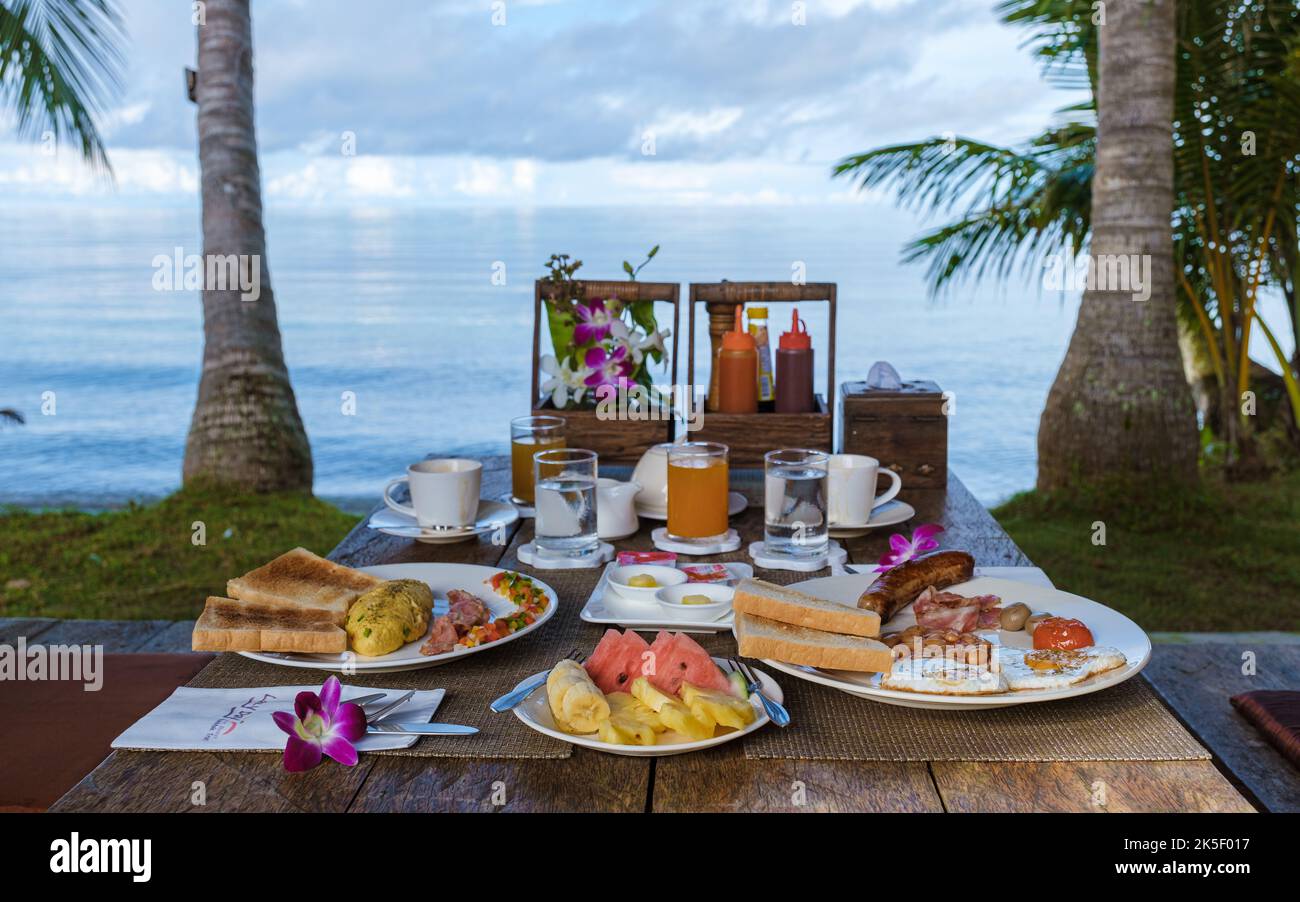 breakfast table on the beach with palm trees in Thailand. colorful ...