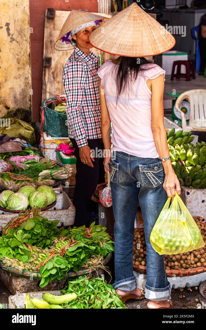 Hawker wearing bamboo hat selling vegetables at food market, Hai Phong ...