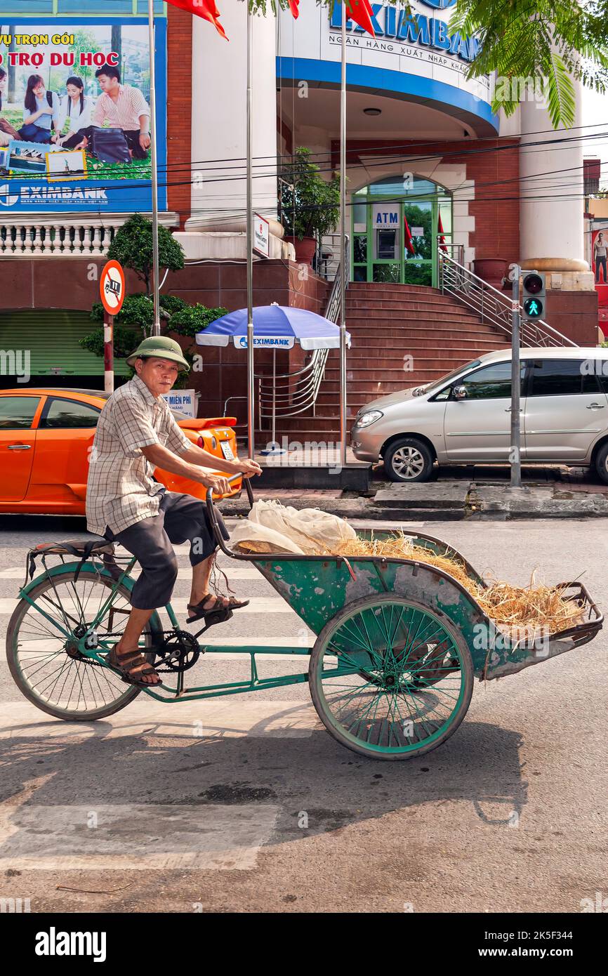 Vietnamese man using bicycle rickshaw to move construction material ...