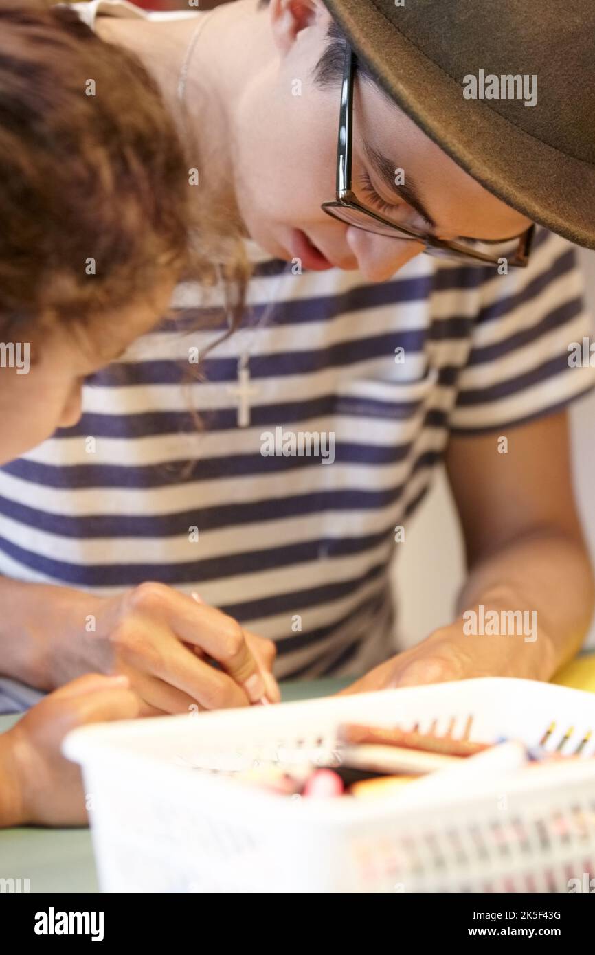 Showing her how its done - Teaching. Young teachers aid helping a child ...