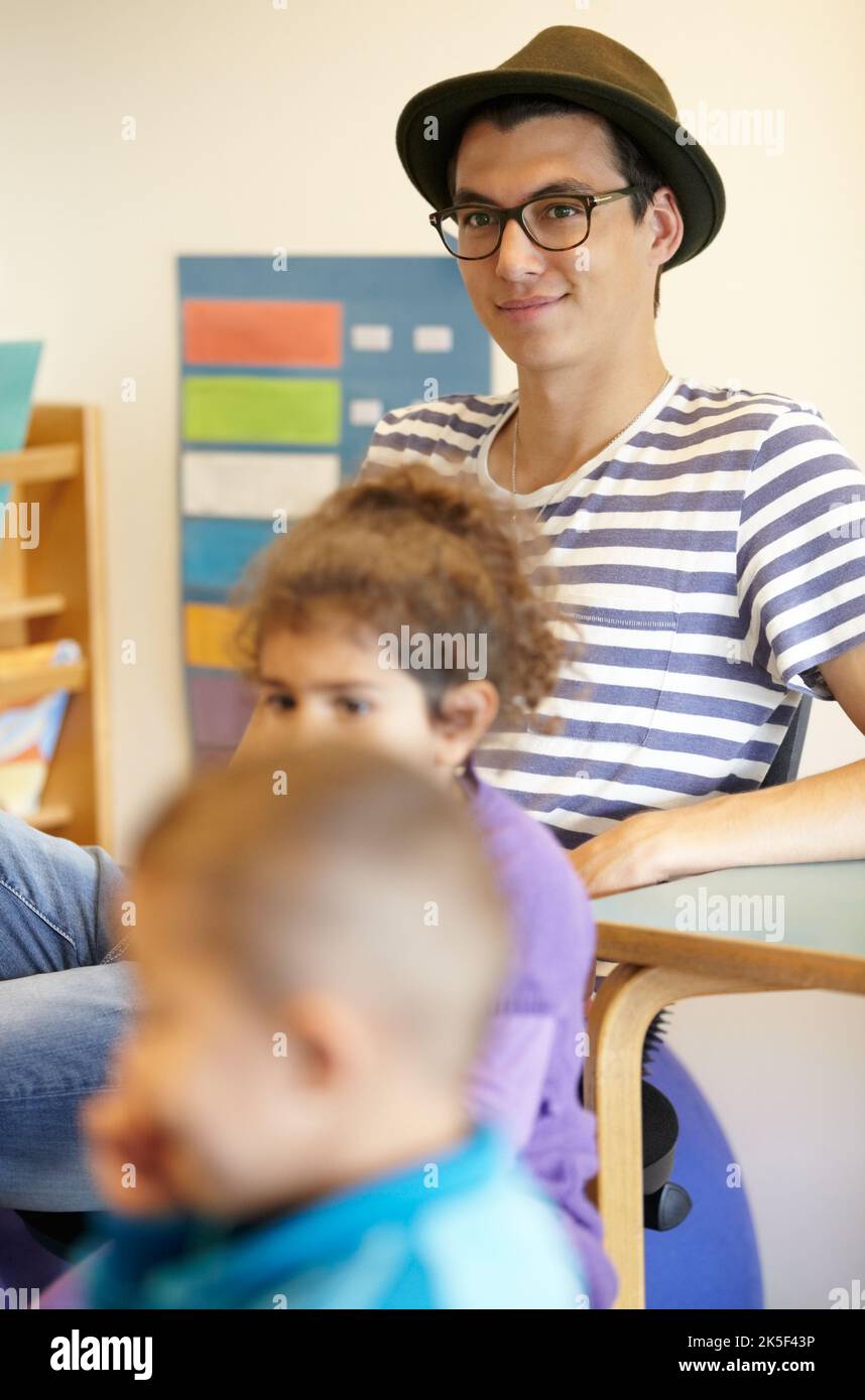 Listening and learning. Young teachers aid sitting in a classroom at a ...