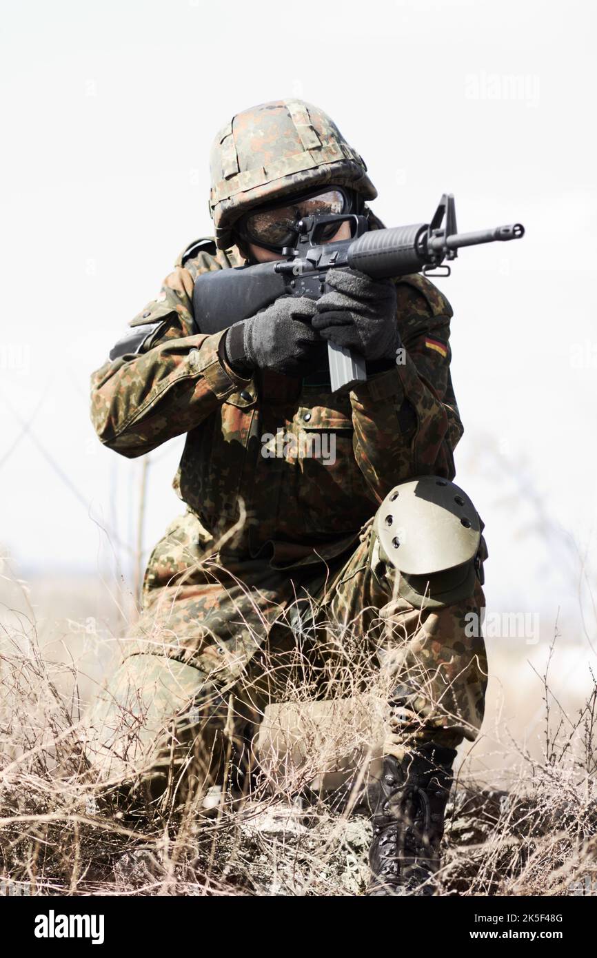 Waiting and watching. A soldier crouched down with gun in hand and ...