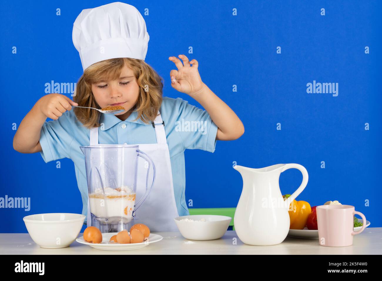 Kid boy in chef hat and apron cooking preparing meal. Little cook with ...