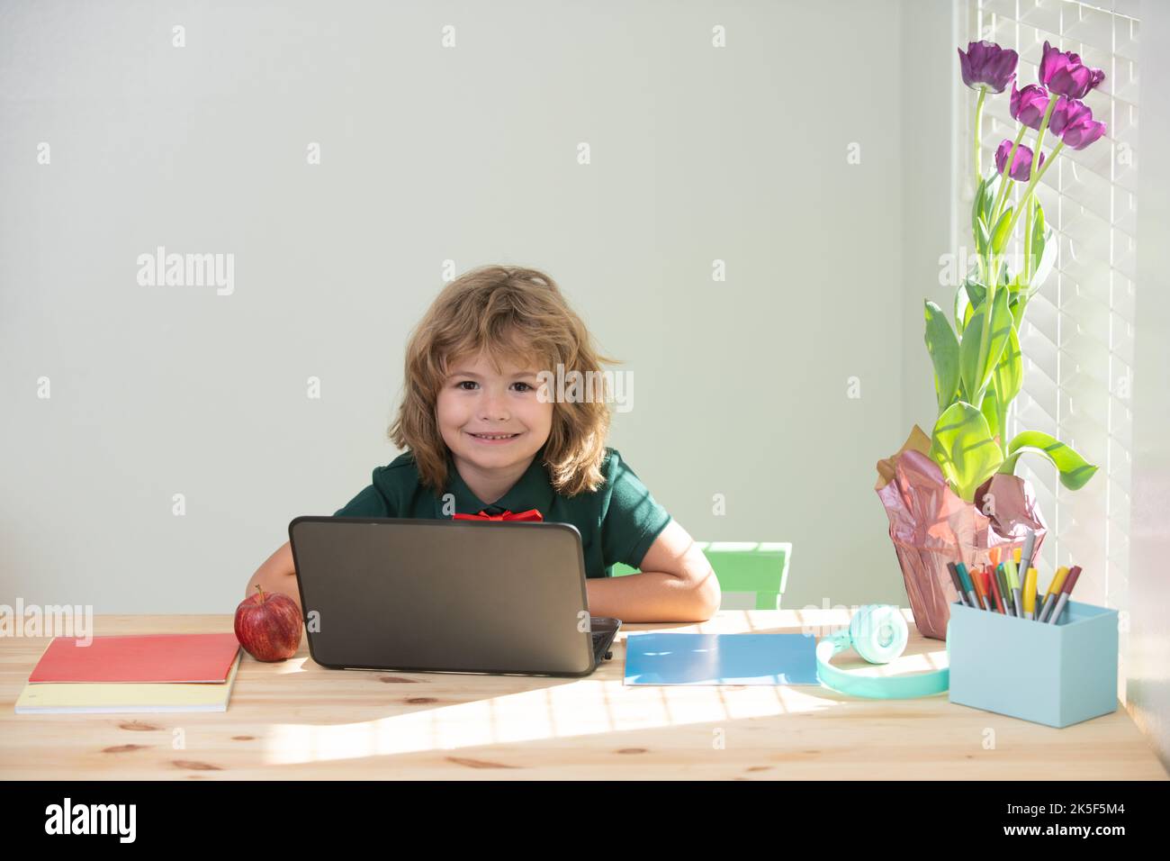 School boy doing her homework with laptop. Child using gadgets to study ...
