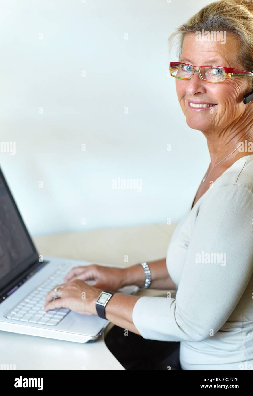 Getting connected. Portrait of a happy senior woman wearing a bluetooth ...