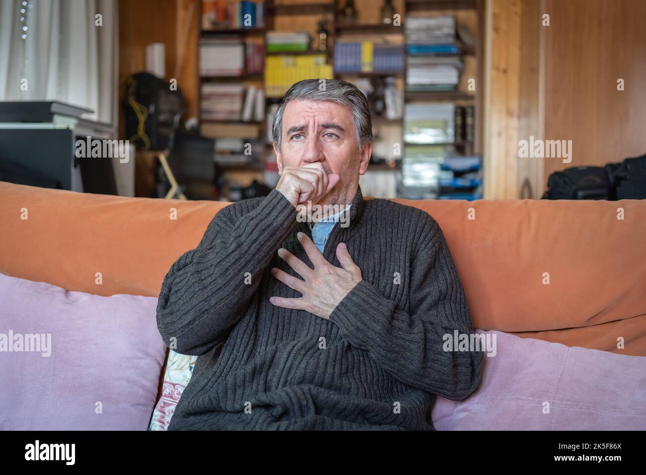 Sick man sitting at home and with a coughing fit from respiratory ...