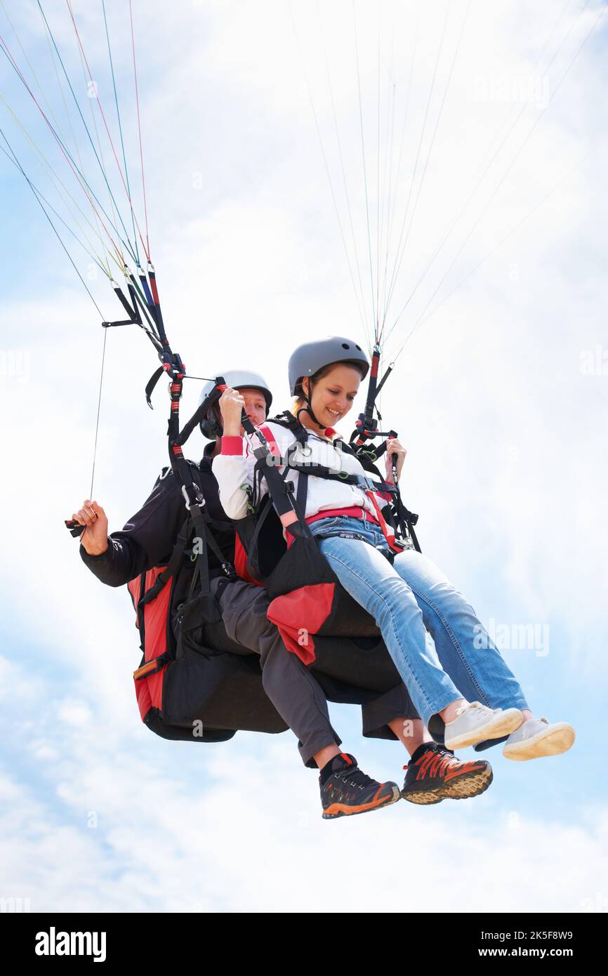 Getting ready to land. Two people in mid-air doing tandem paragliding ...