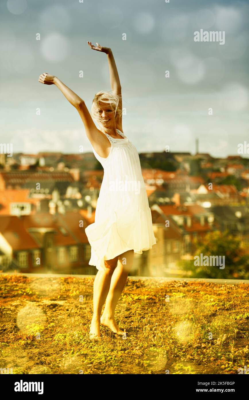 Fun in the sun. A gorgeous young woman dancing surrounded by bokeh ...