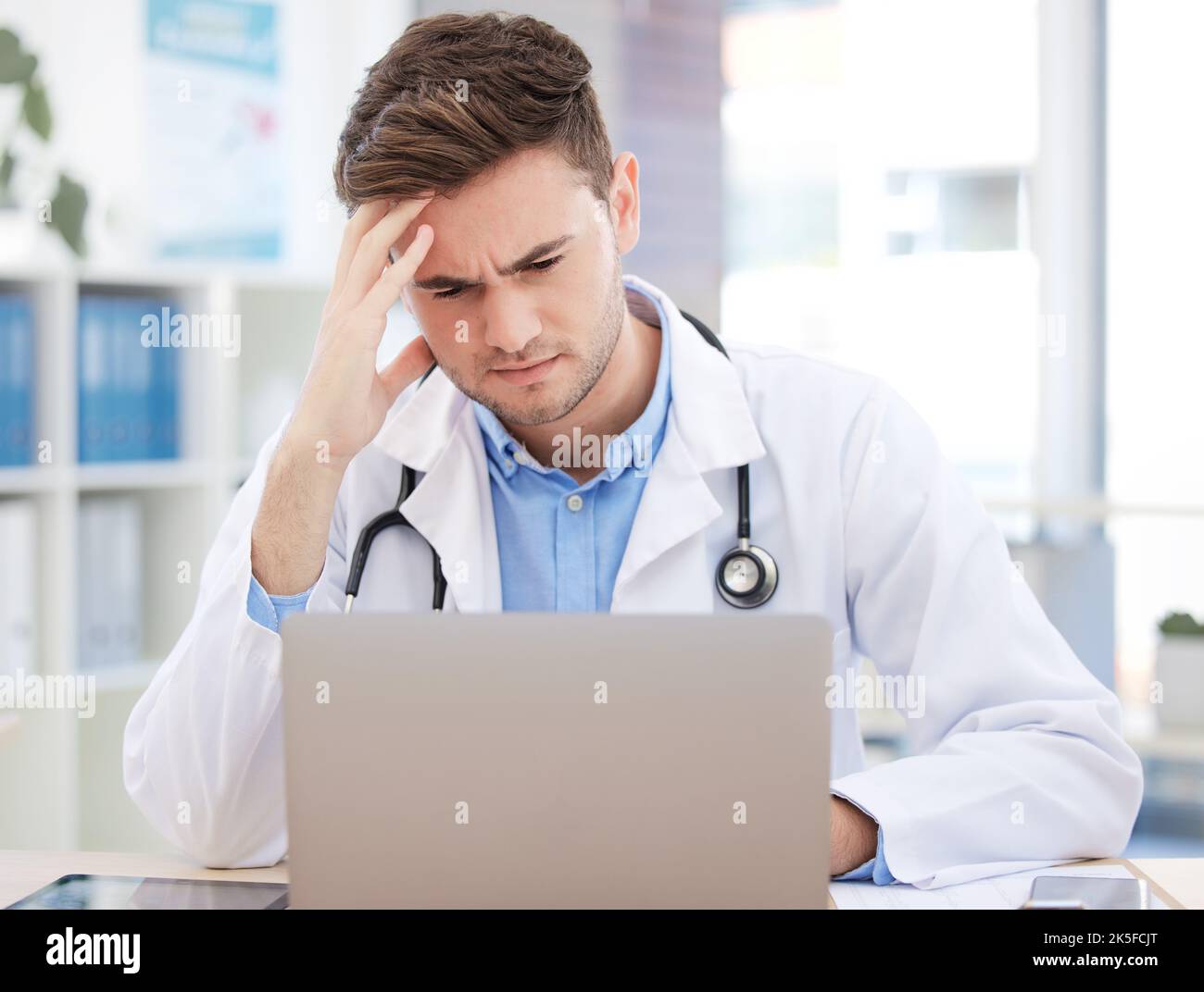 Doctor, computer working and work headache of a man healthcare worker ...