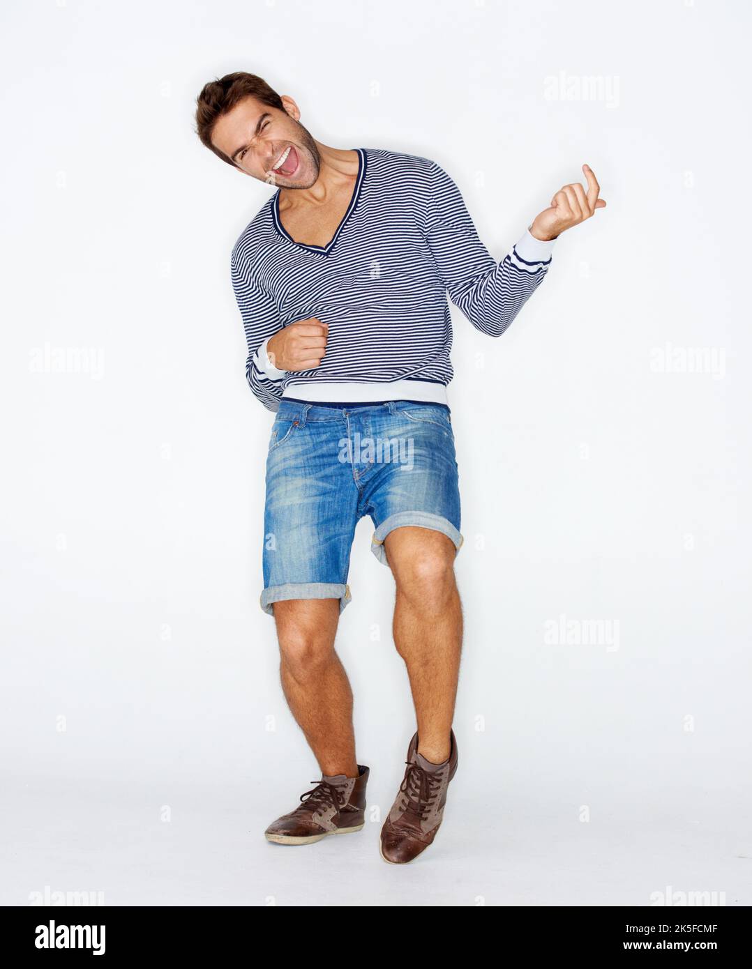 Rocking out. Handsome young guy playing air guitar while against a ...