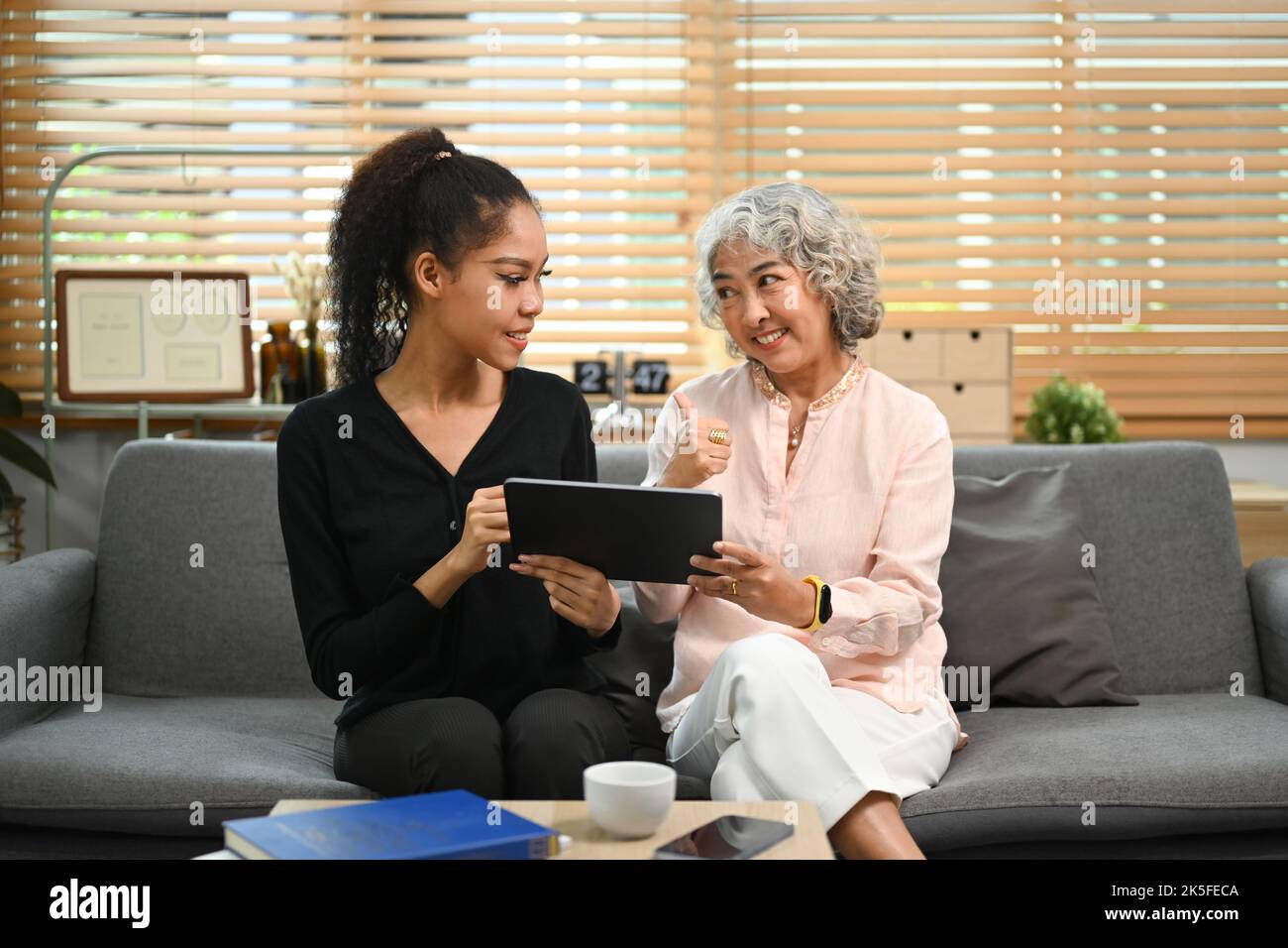 Caring young woman showing useful applications, teaching retired mother ...