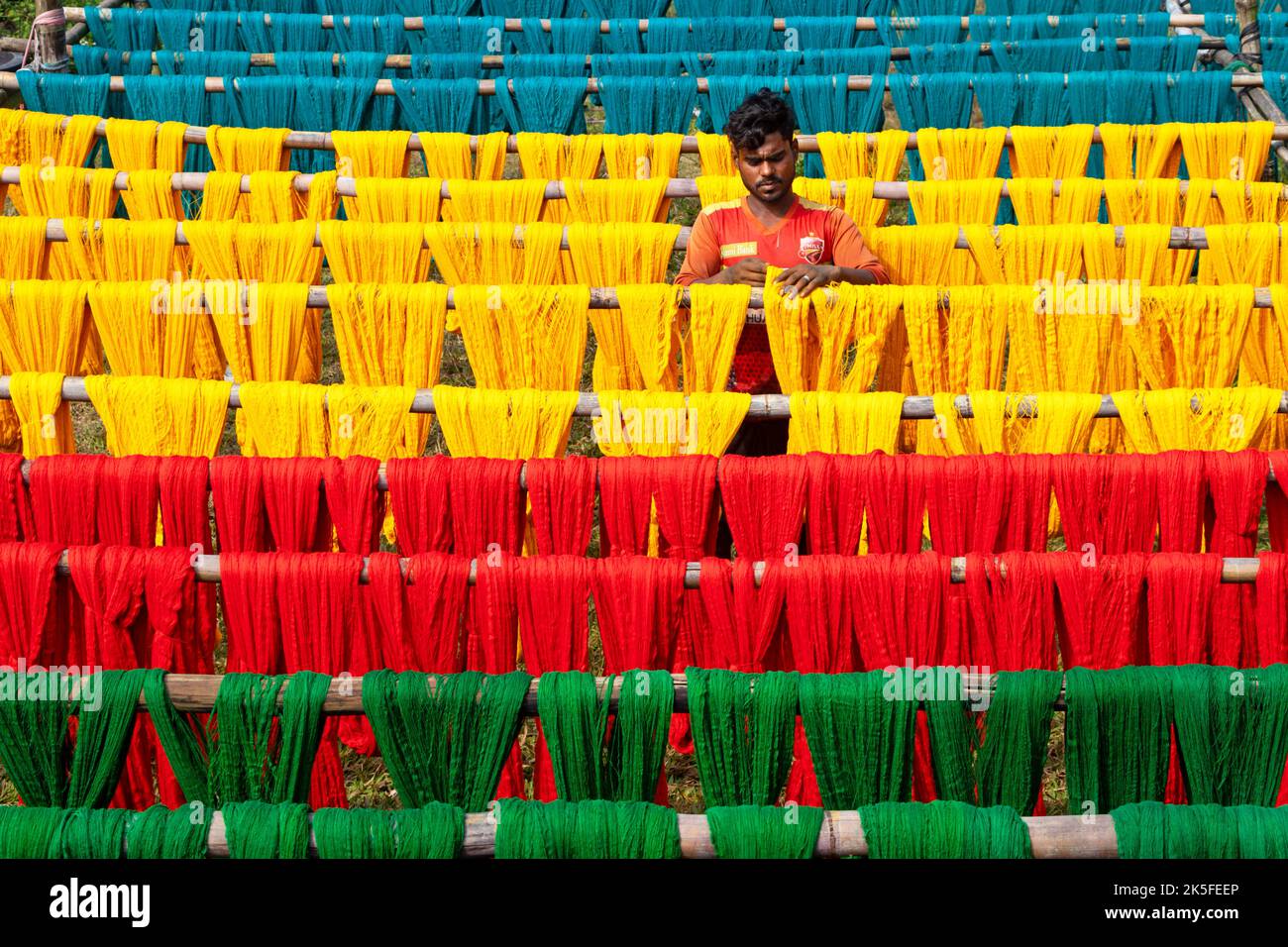 Workers hang thousands of freshly dyed colorful threads on a wooden ...