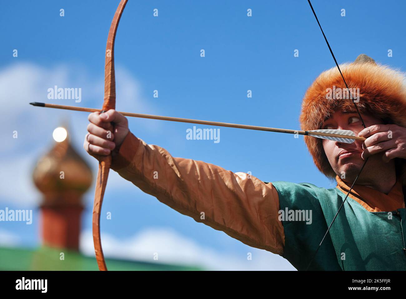 Medieval archery tournament. Man shoots an arrow in the medieval castle ...