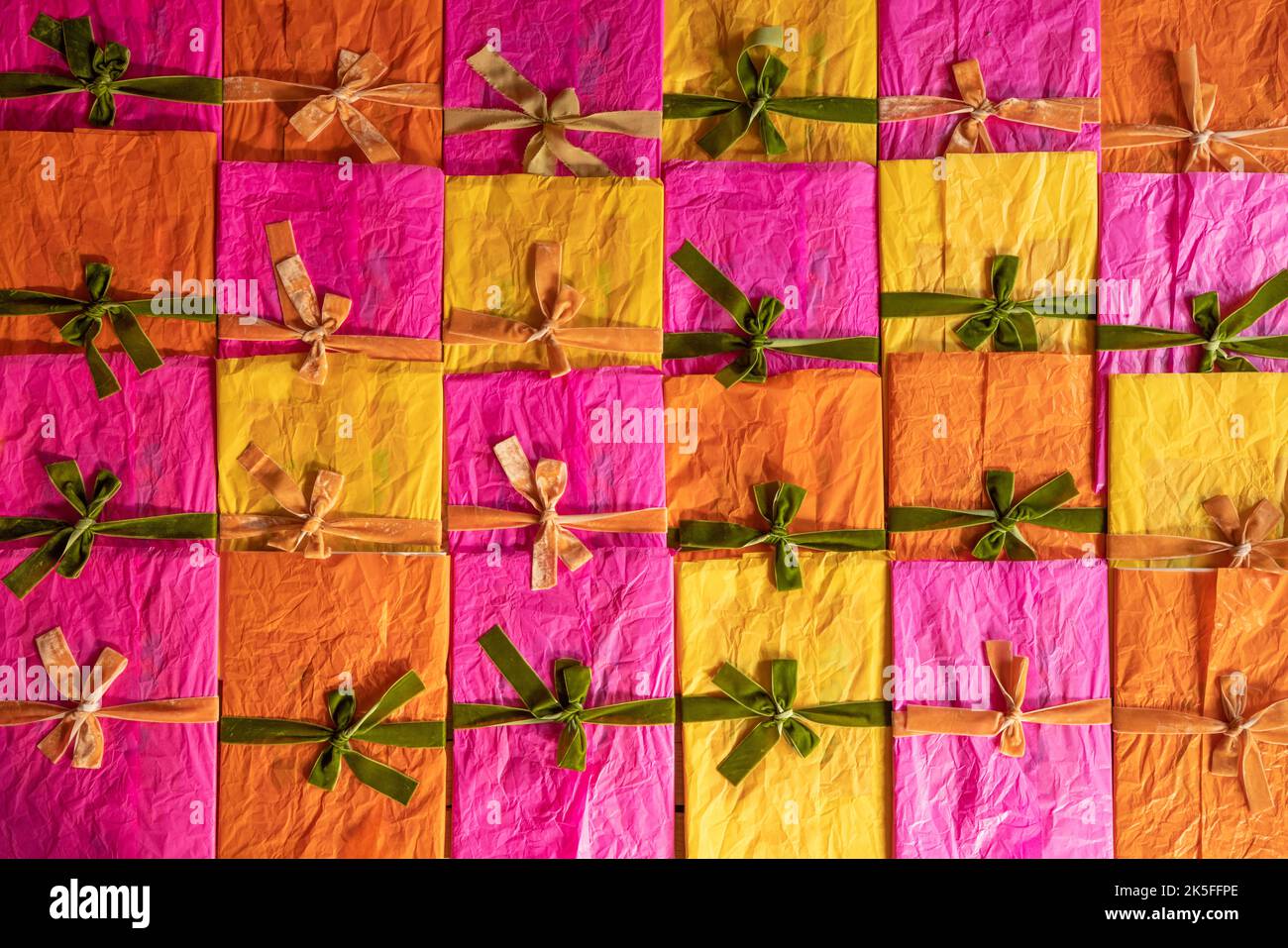 Multi-colored envelopes decorated with ribbons and bows stacked ...