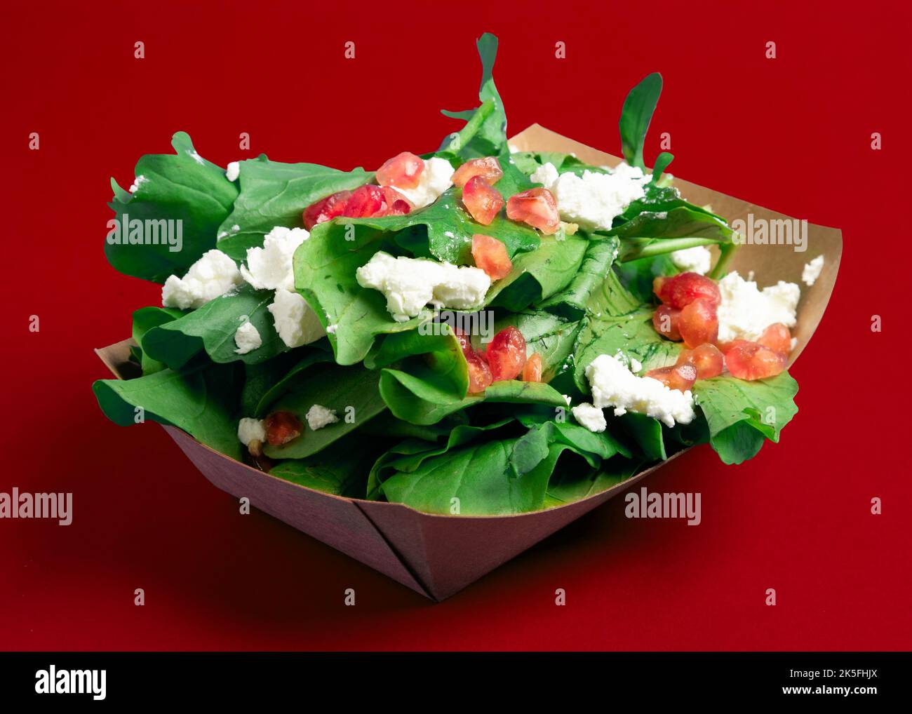 A closeup of Rocca salad with feta cheese and pomegranate in red ...