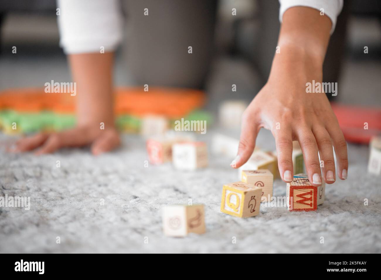 Hands, cleaning and toys with a woman or mother picking up building ...