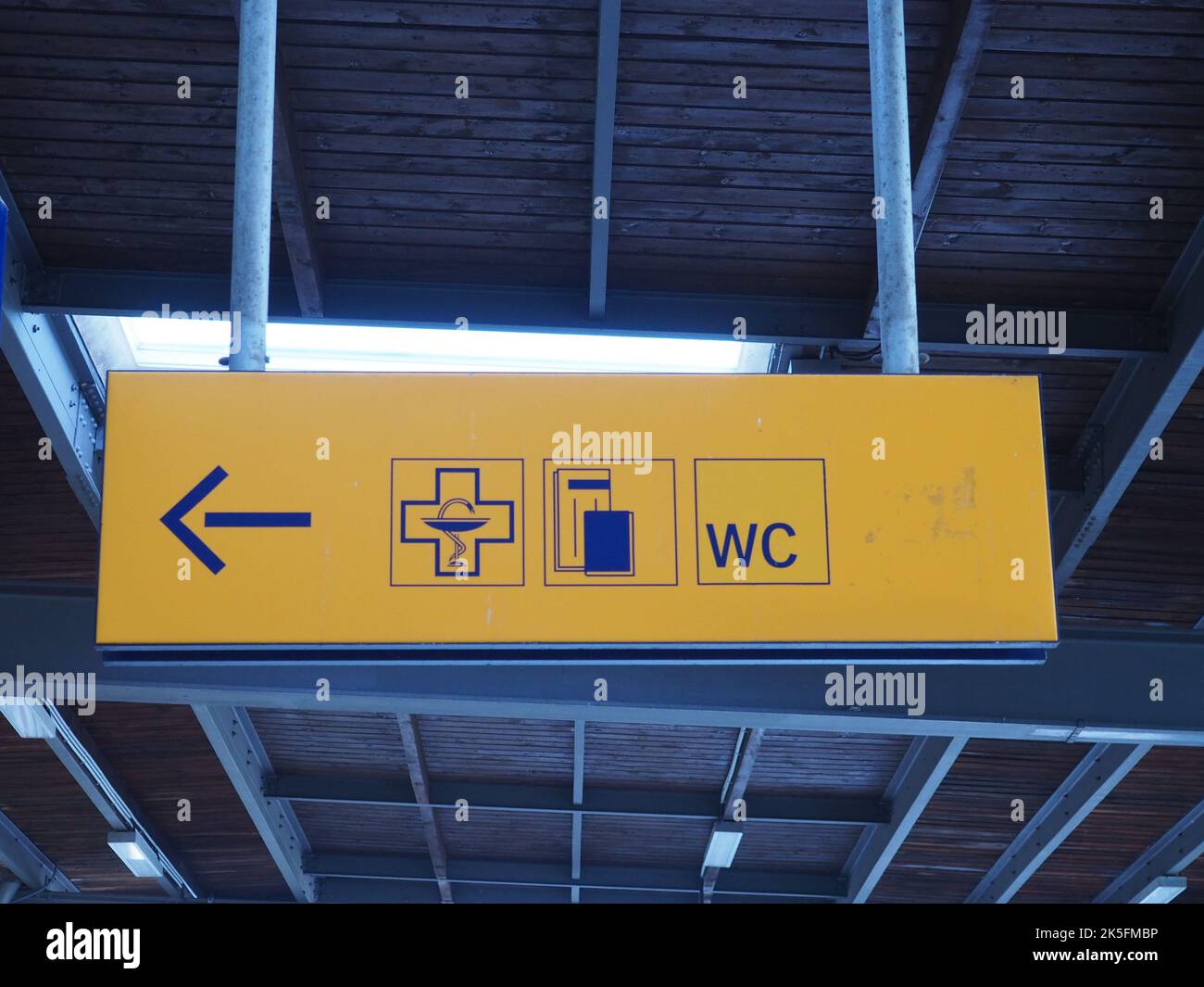 Hanging yellow sign of directions to the toilets, pharmacy, and ...