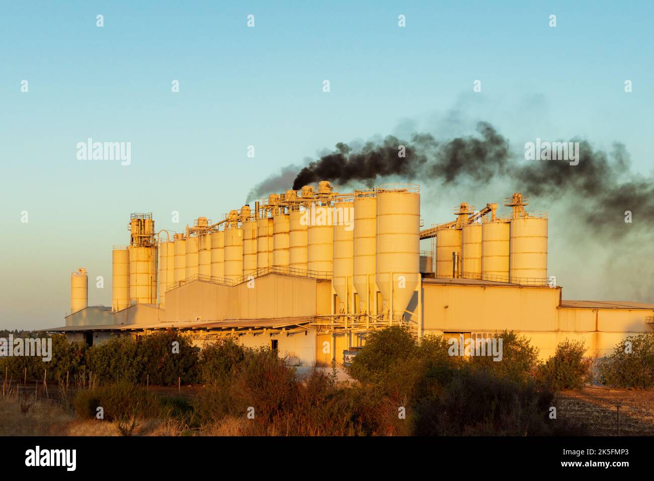 Silos of a factory with a chimney emitting a large amount of black ...