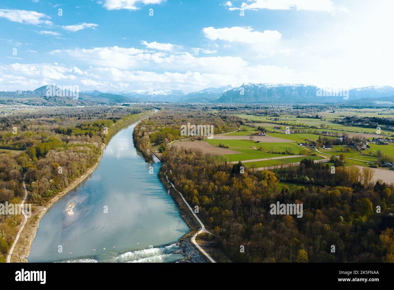 An aerial view of Salzach river in Salzburg surrounded by greenery on a ...