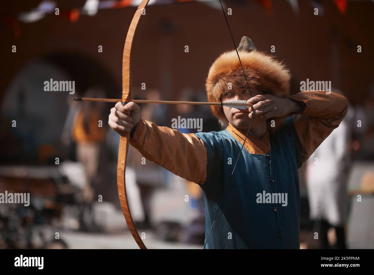 Medieval archery tournament. Man shoots an arrow in the medieval castle ...