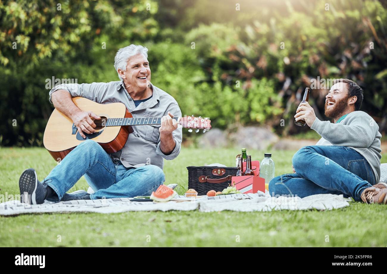 Guitar, father and son on park picnic with beer and music during ...