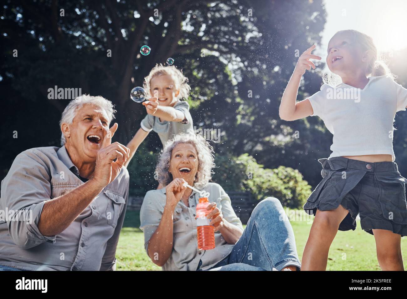 Grandparents, bubbles and children play in park happy together for fun ...