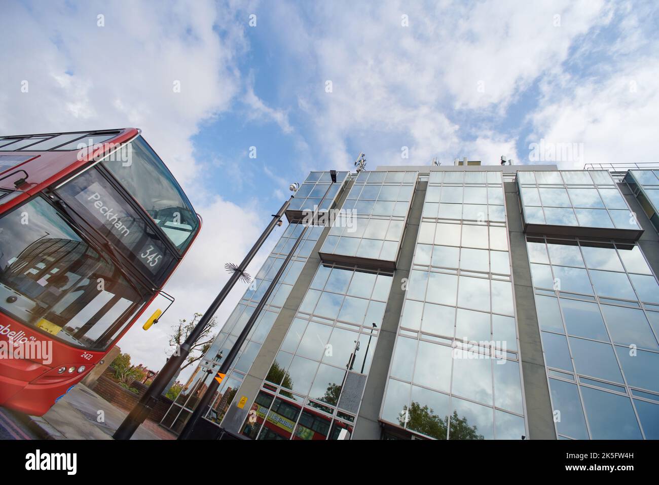 Double decker bus passing a modern office building with glass facade in ...