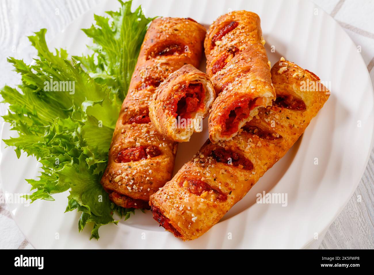 chorizo and semi-dried tomato puff pastry rolls on white plate and ...