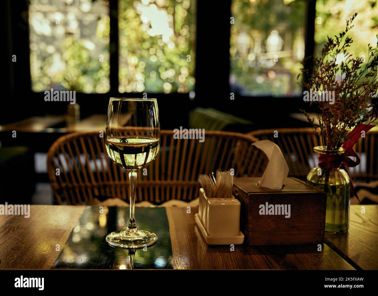 A glass of white wine on a restaurant table with a reflection of the ...