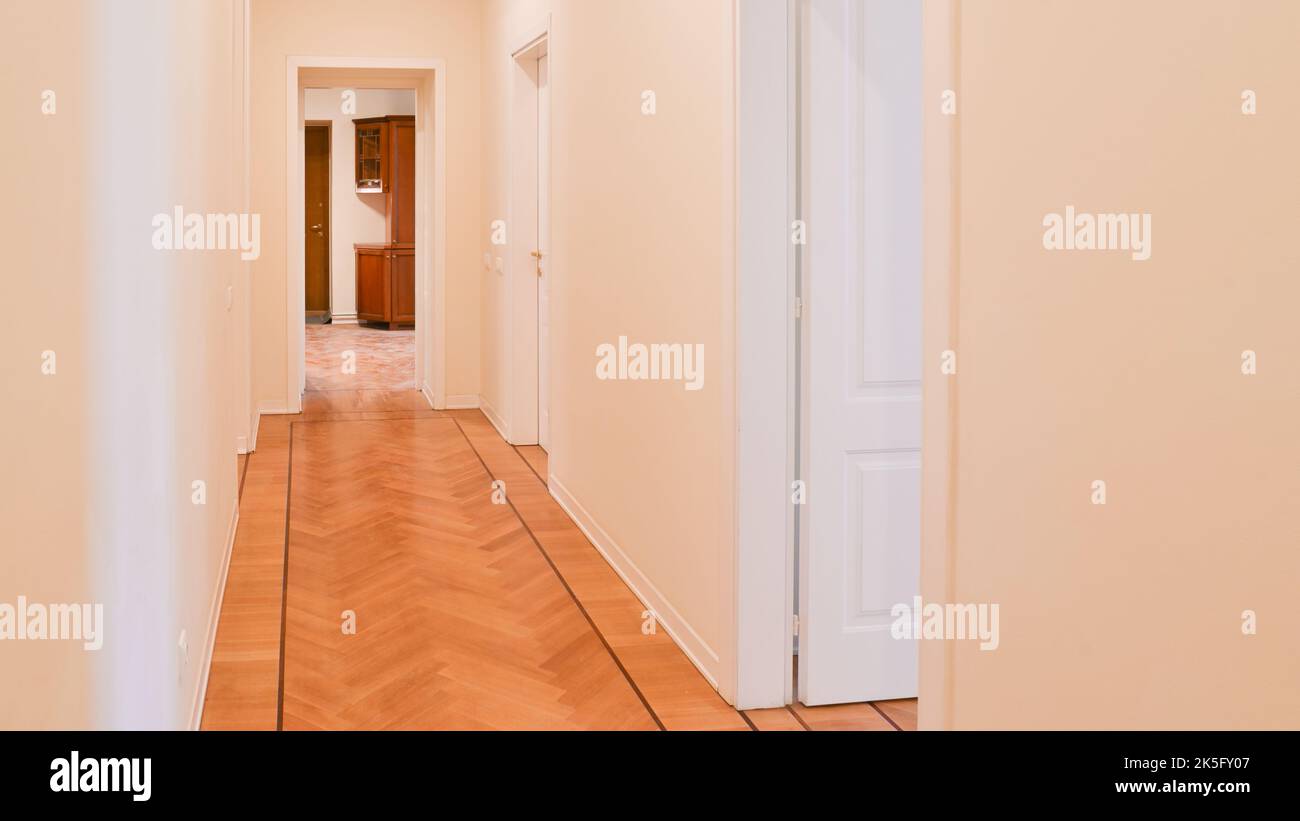 Corridor in a house with wooden floor white walls and doors to rooms ...