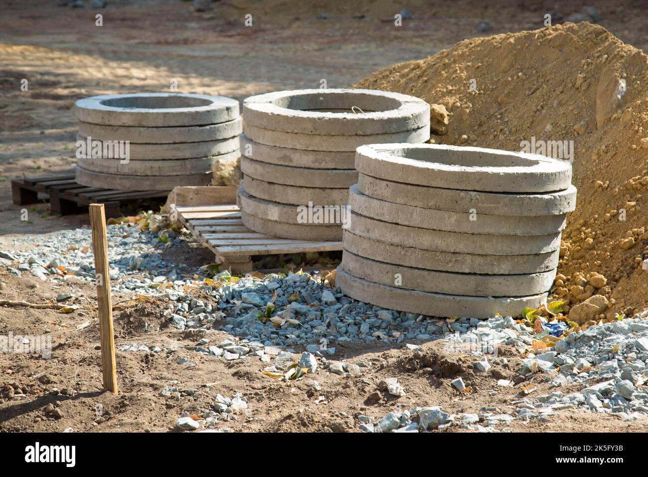 Reinforced concrete rings lie on pallets at the construction site Stock ...
