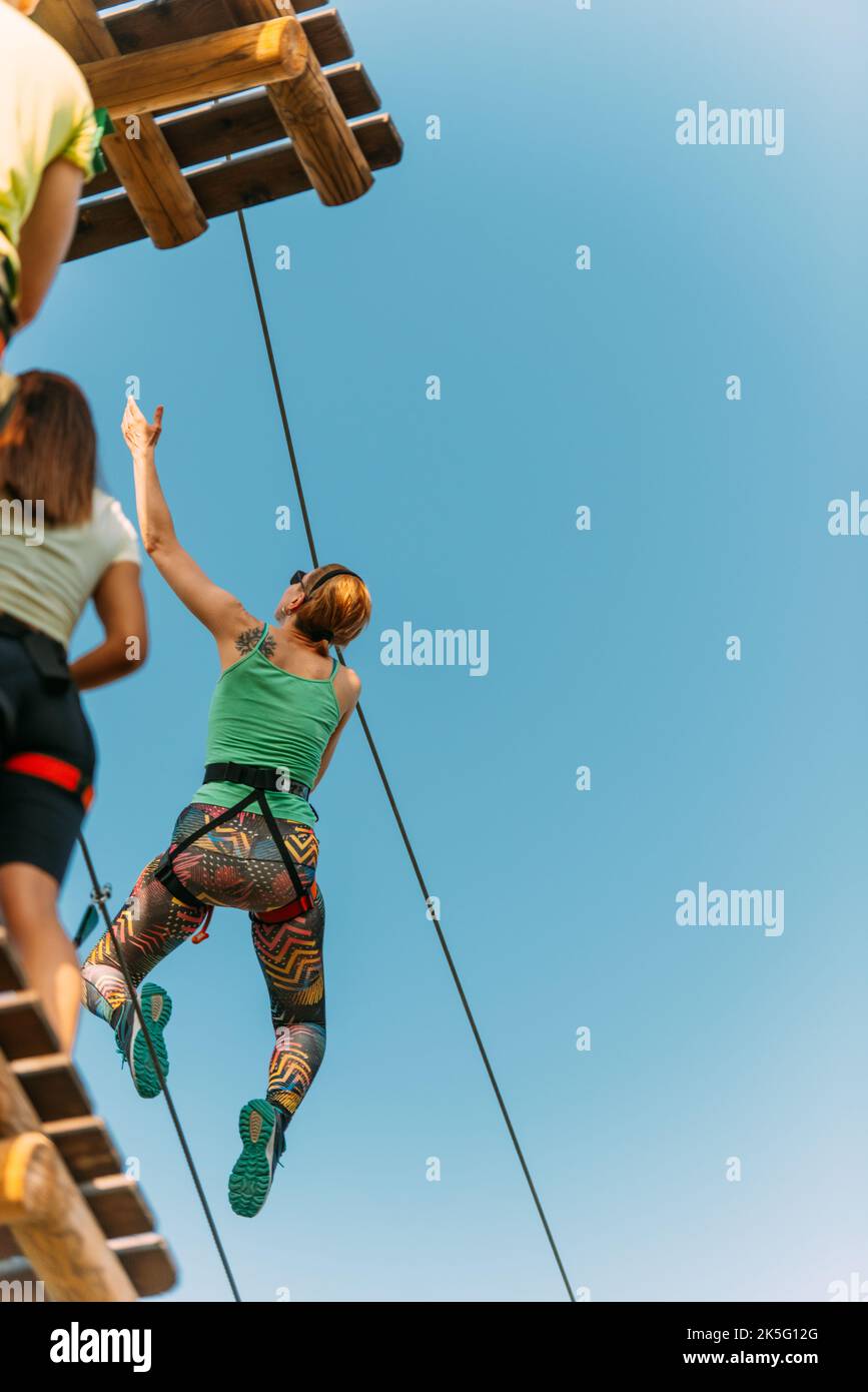 Athletic young woman going down a zip line in the adventure park Stock ...
