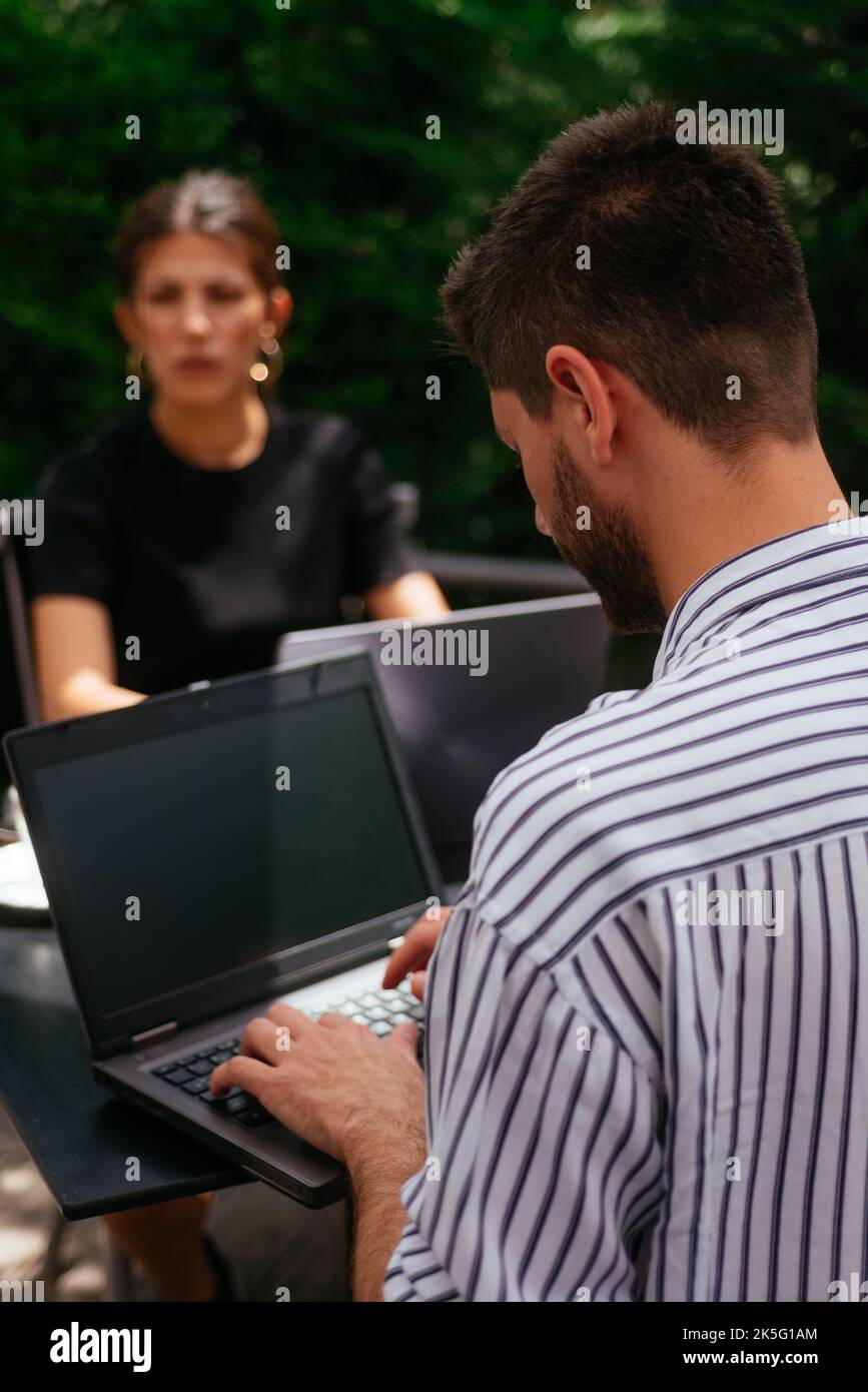 A handsome businessman is working on his lap top while his female ...